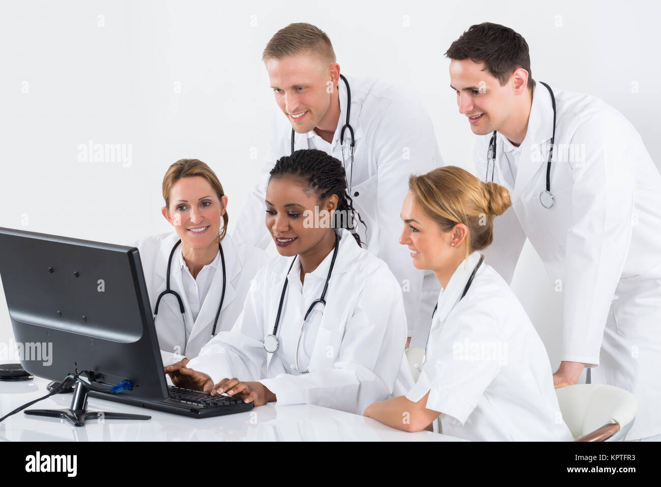 Group Of Doctors Looking At Computer At Desk Stock Photo - Alamy