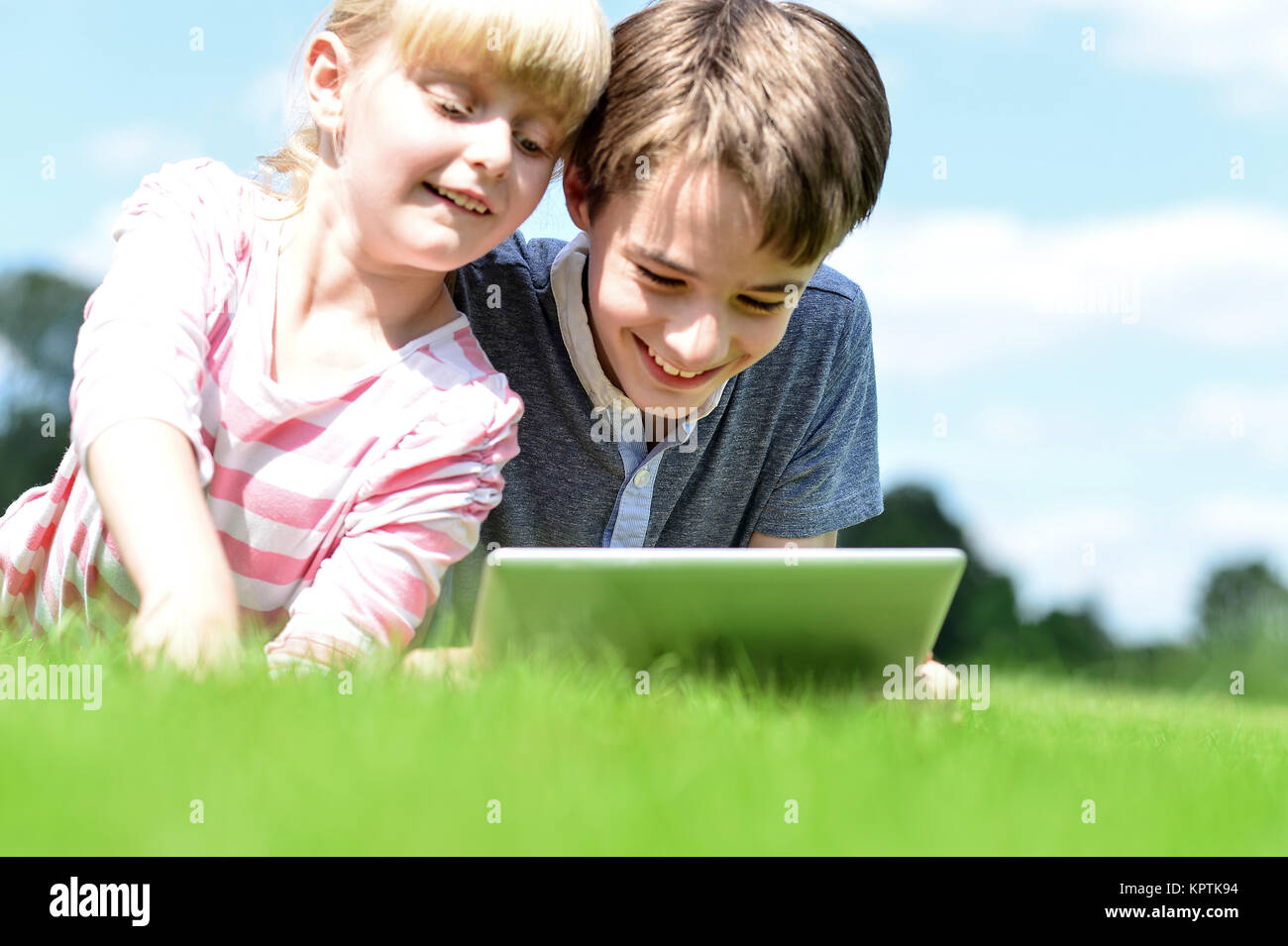 Happy children using tablet PC Stock Photo - Alamy
