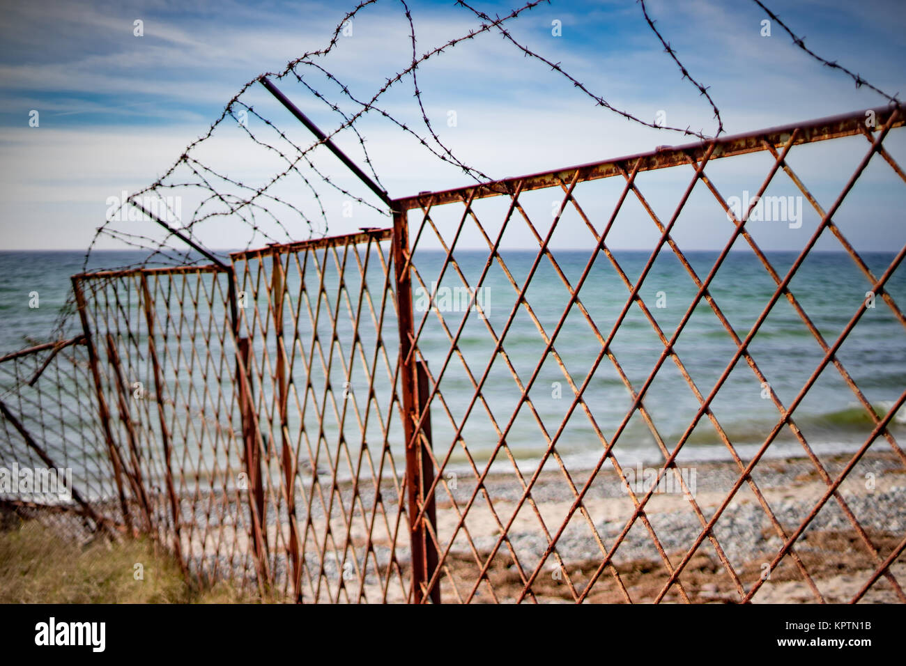 old barbed wire fence on the beach in front of blue water Stock Photo ...