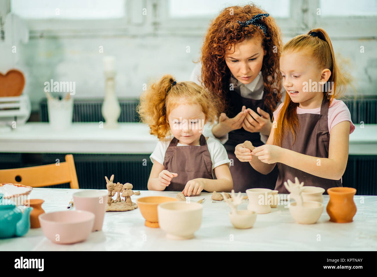 redhead mother and two daughter mold with clay, pottery children Stock ...