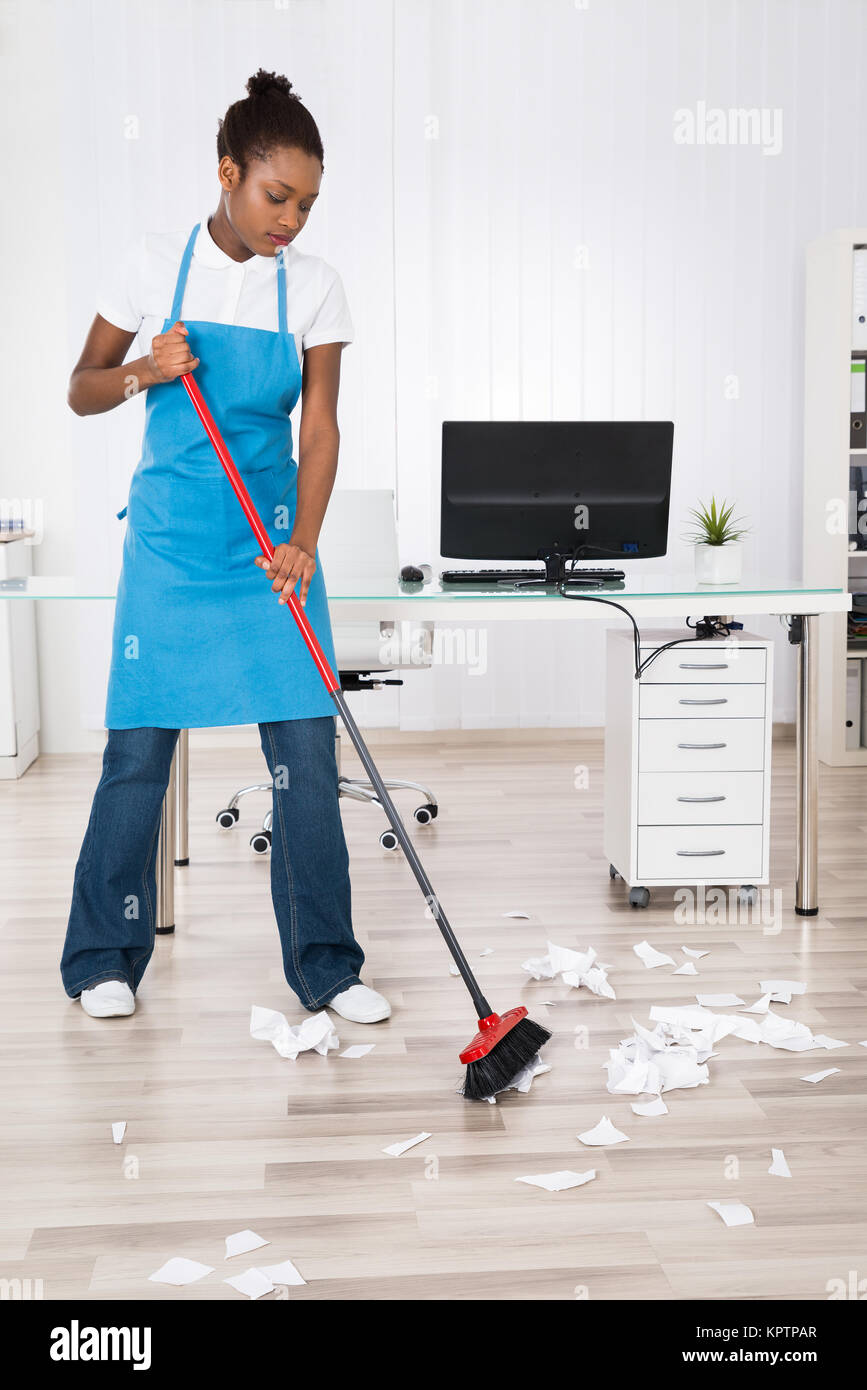 Young Female Janitor Sweeping Torn Paper Pieces On Hardwood Floor Stock ...