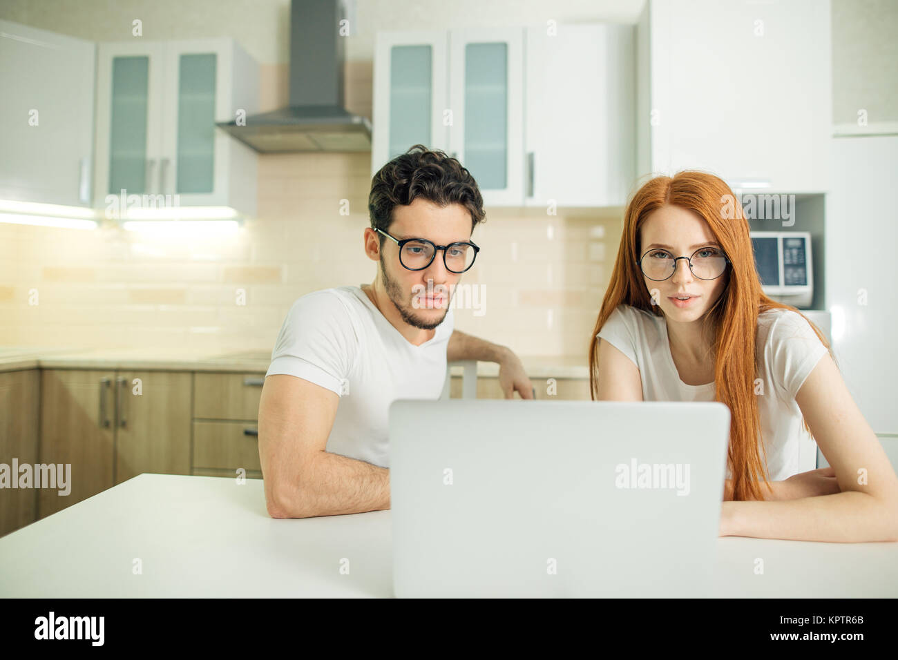 couple browsing internet together sitting at table and smiling and read ...