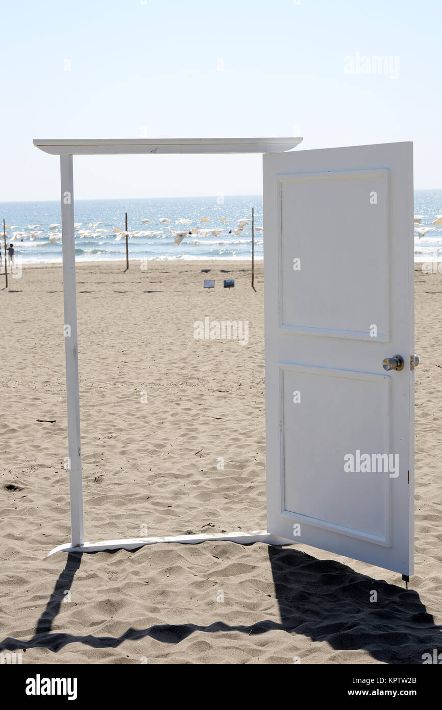 White door on the beach, opened to a view of coast Stock Photo - Alamy