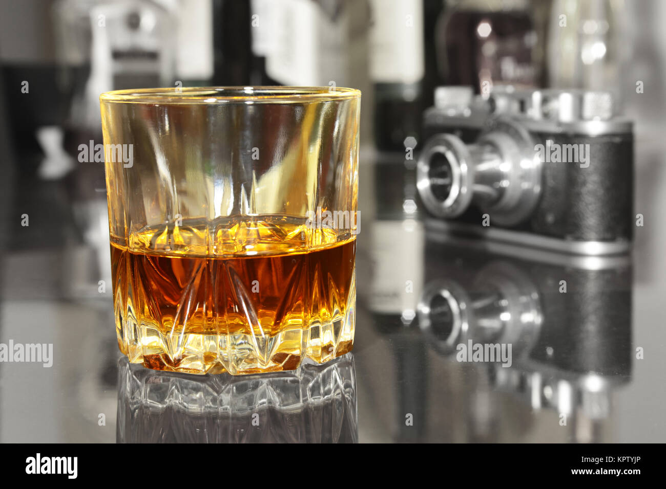 Glass of wine, cognac, brandy or whiscy on mirror table. bottles in a ...