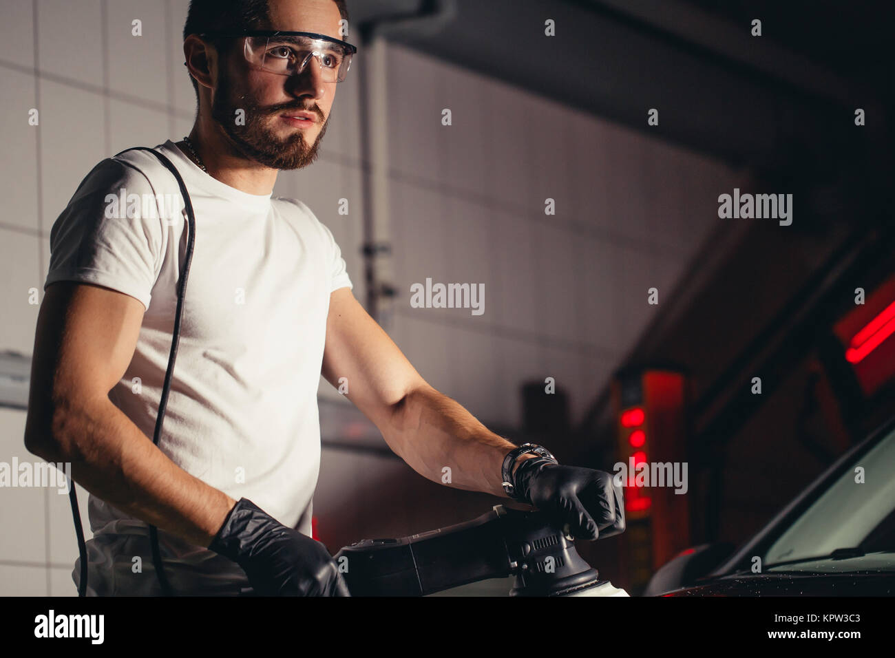 Car detailing - man with orbital polisher in auto repair shop ...