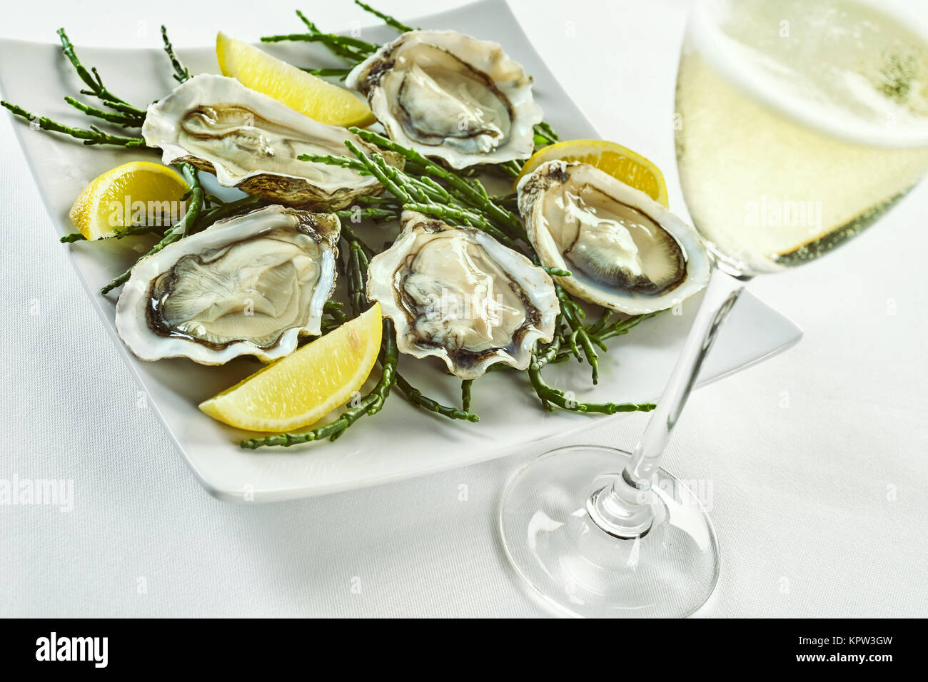 Open oyster shells with lemon wedges in plate with curled edges and ...