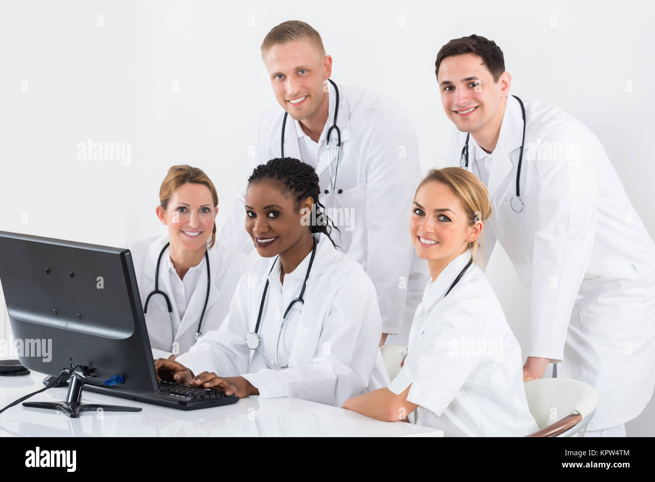 Group Of Doctors Looking At Computer At Desk Stock Photo - Alamy