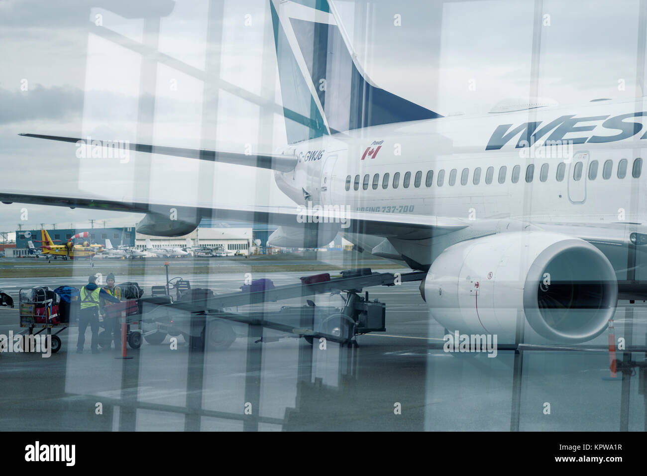 Artistic photo of Checked in luggage being loaded on a WestJet airplane ...