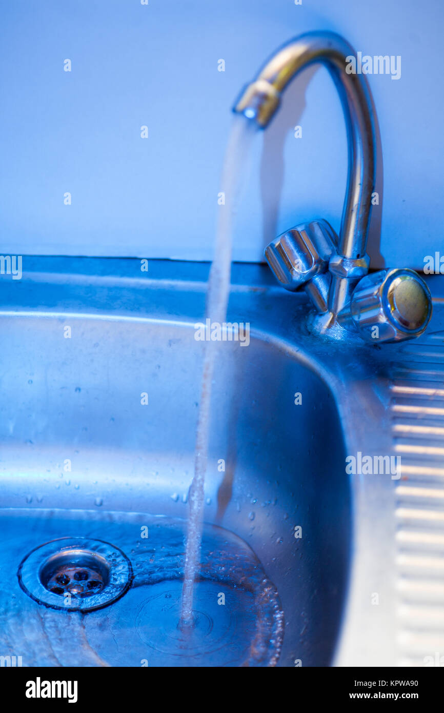 A stream of clean, transparent fresh water flows from the steel shiny ...