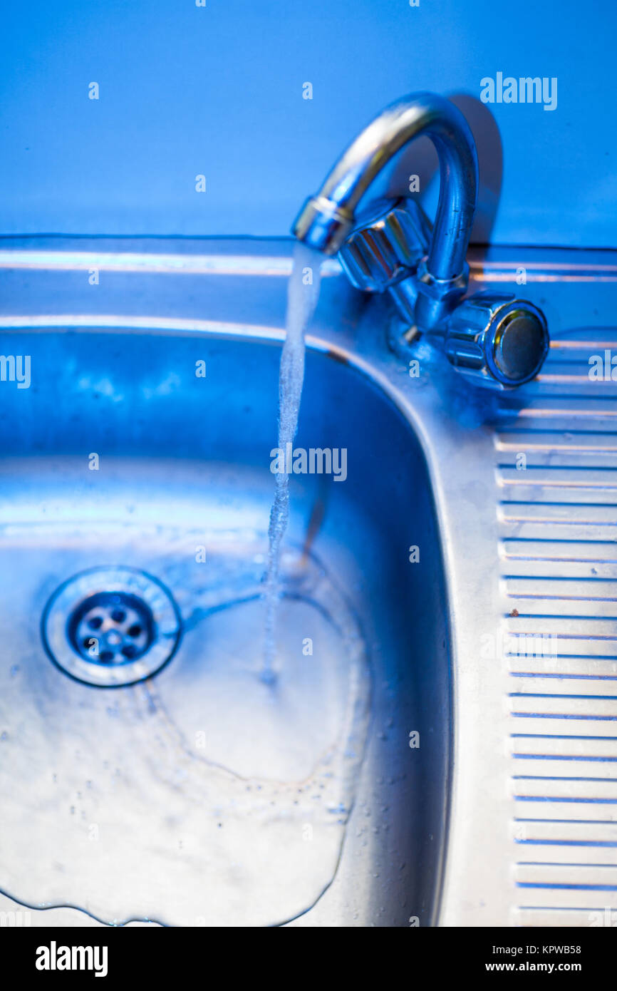 A stream of clean, transparent fresh water flows from the steel shiny ...