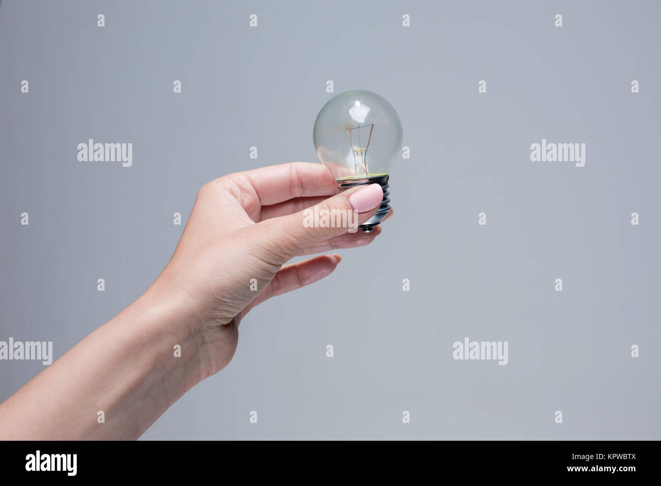 Hand holding an incandescent light bulb on gray background Stock Photo ...