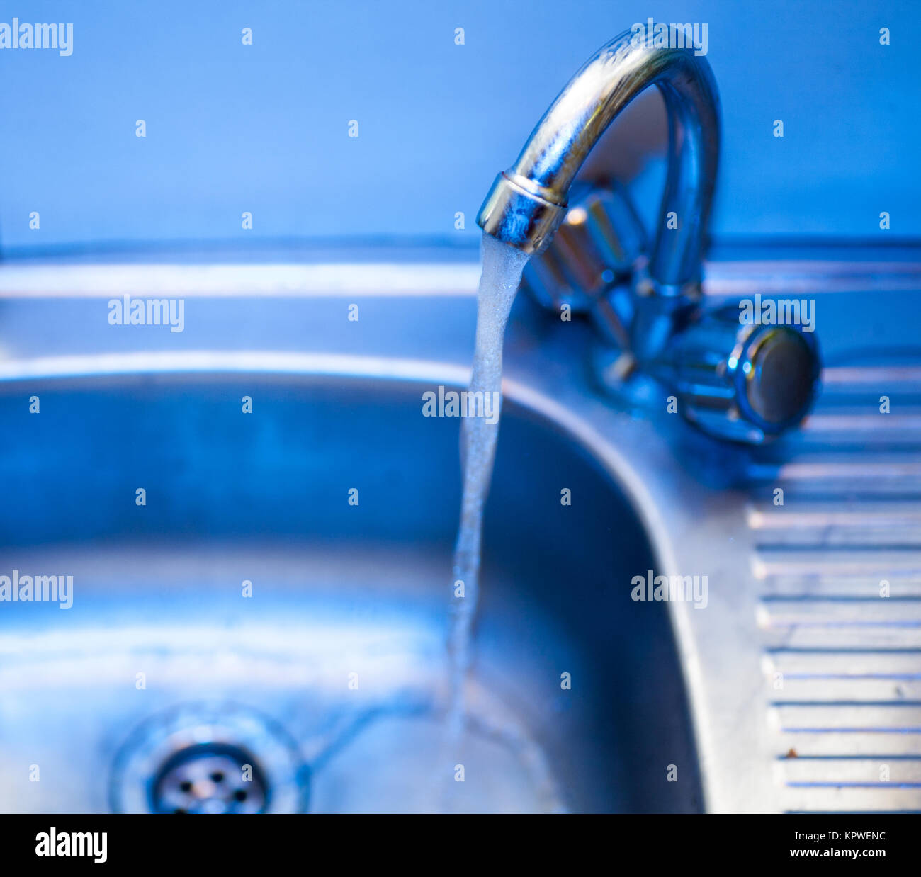 A stream of clean, transparent fresh water flows from the steel shiny ...