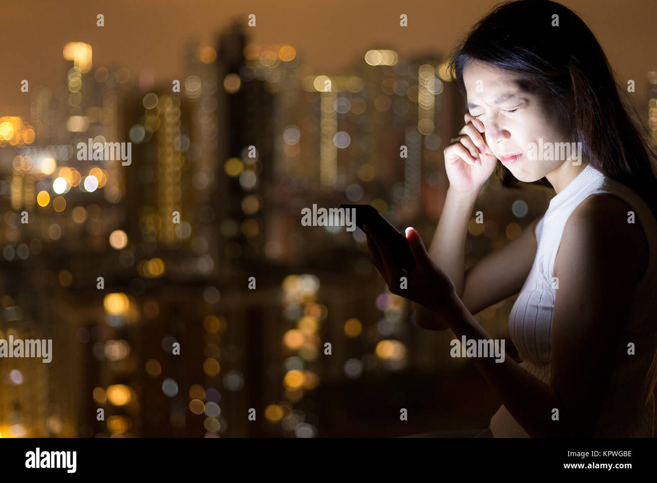 Woman feeling eye pain when using mobile phone at night Stock Photo - Alamy