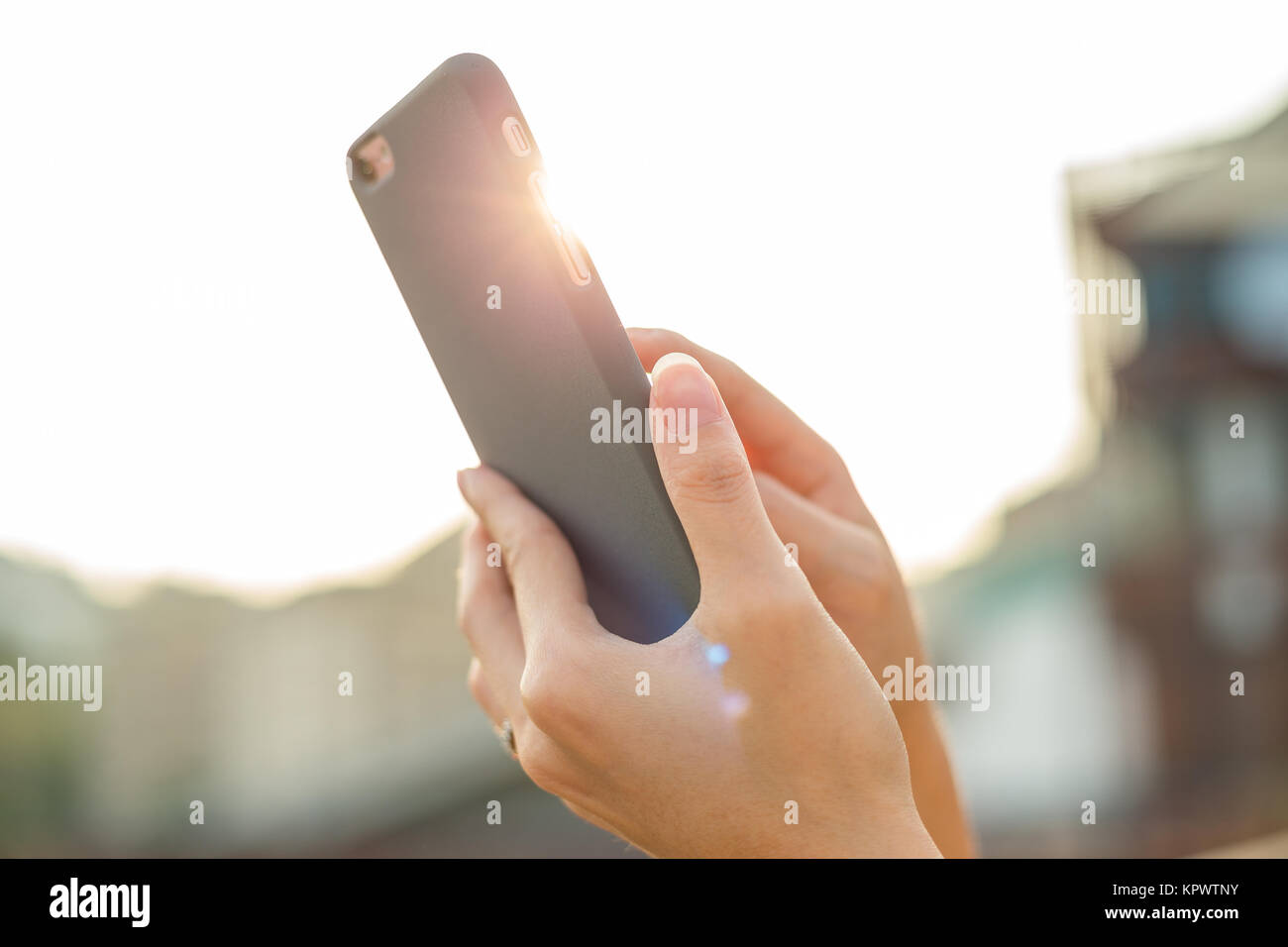 Woman use of mobile phone with sun flare Stock Photo - Alamy