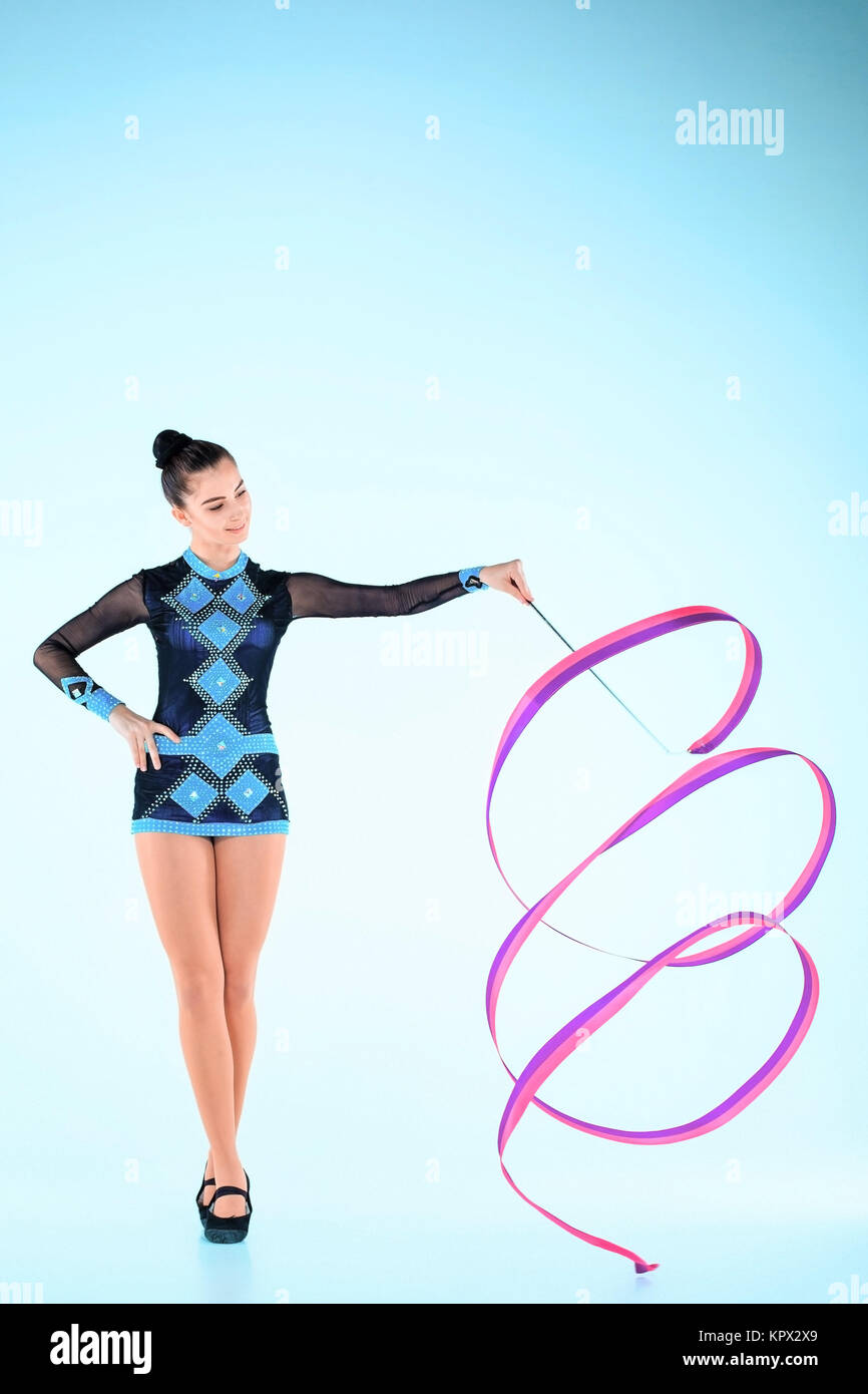 The girl doing gymnastics dance with colored ribbon on a blue ...