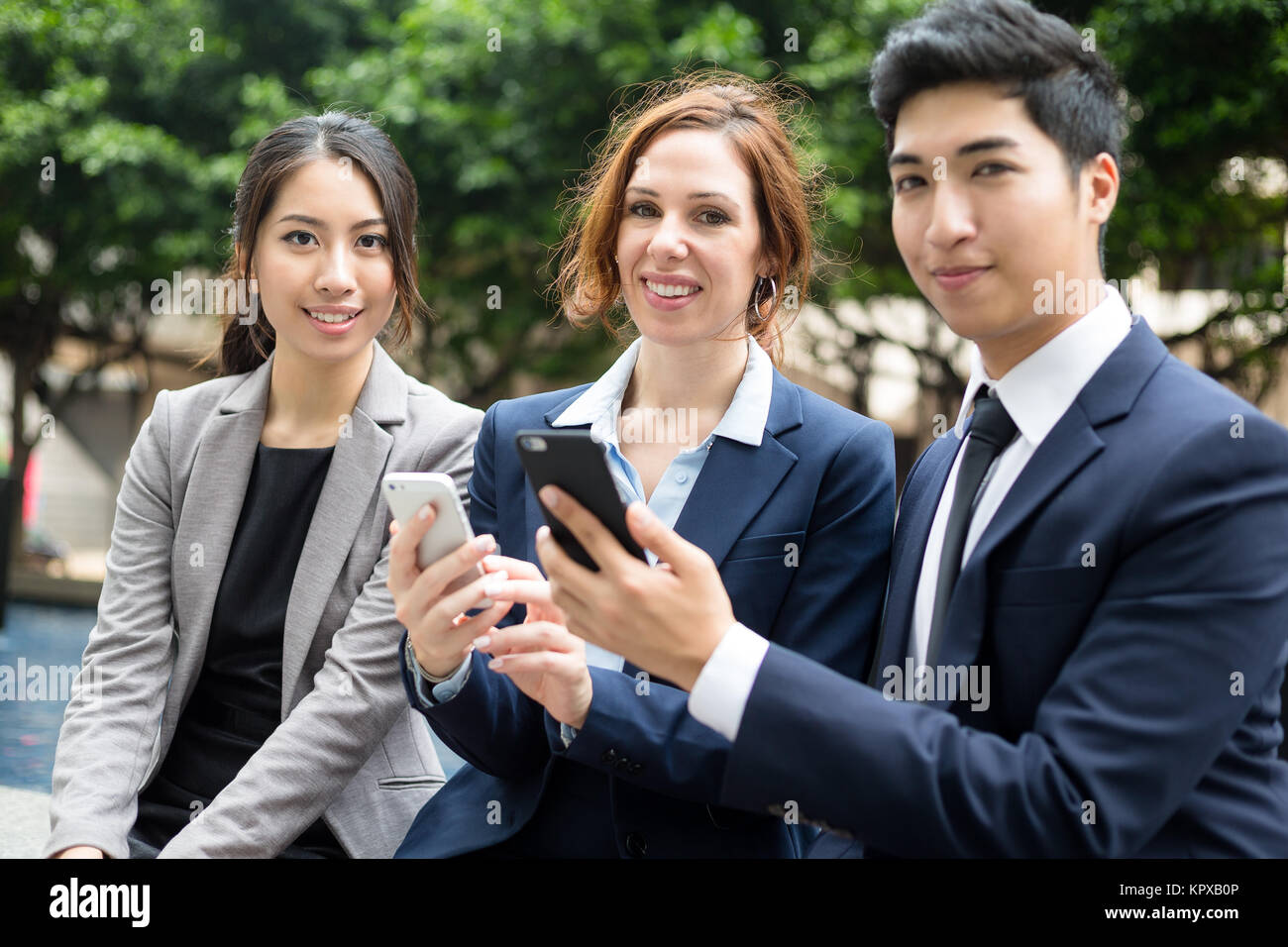 Business people using cellphone together Stock Photo - Alamy