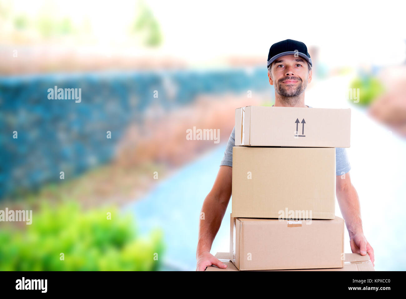 friendly postman with parcels smiling in to the camera Stock Photo - Alamy