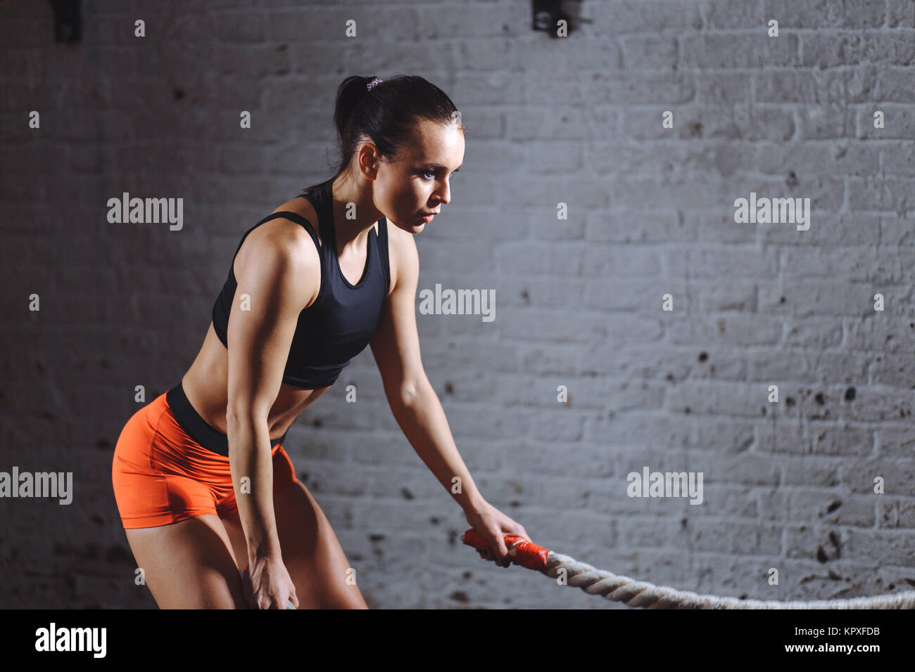 close up photo of Athletic woman doing battle rope exercises at gym ...