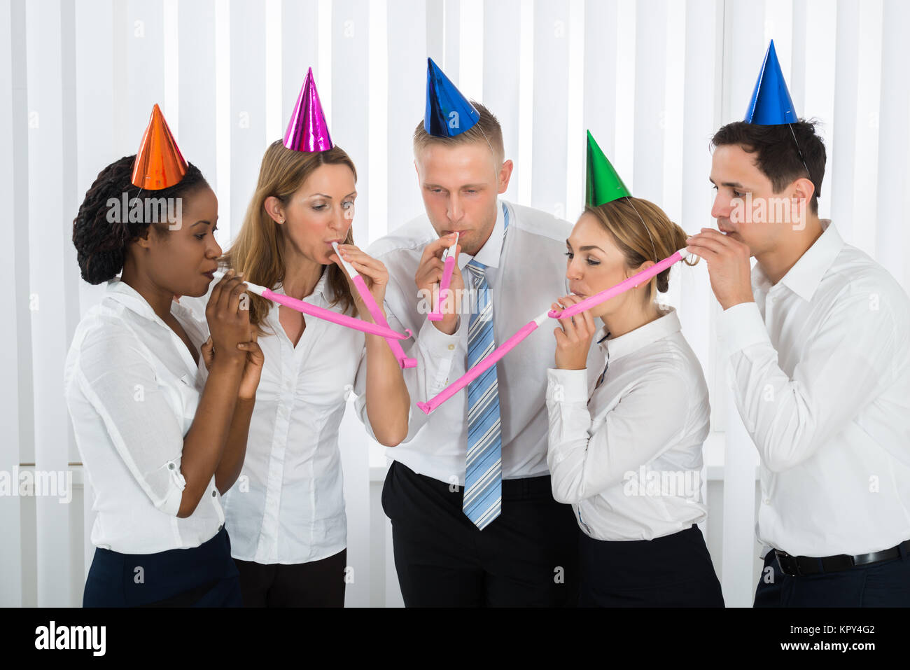 Businesspeople Blowing Party Blower In Office Stock Photo - Alamy