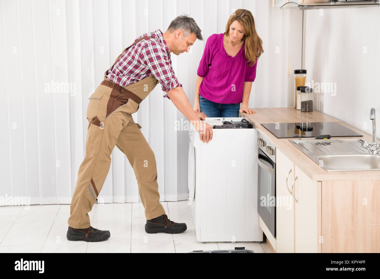 Worker Repairing Washing Machine In Kitchen Stock Photo - Alamy