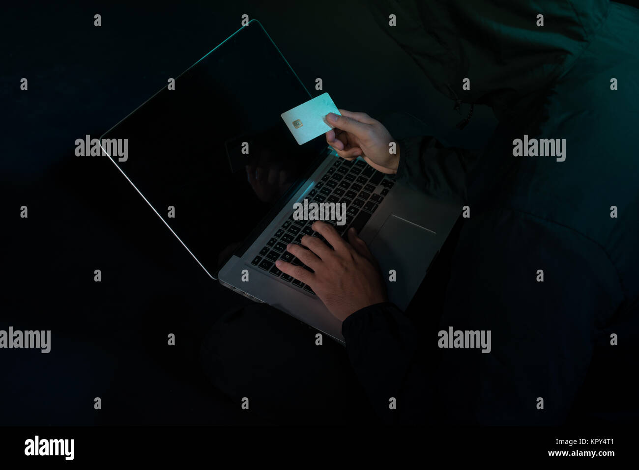 Cyber crime concept: Anonymous man holding credit card with laptop on ...