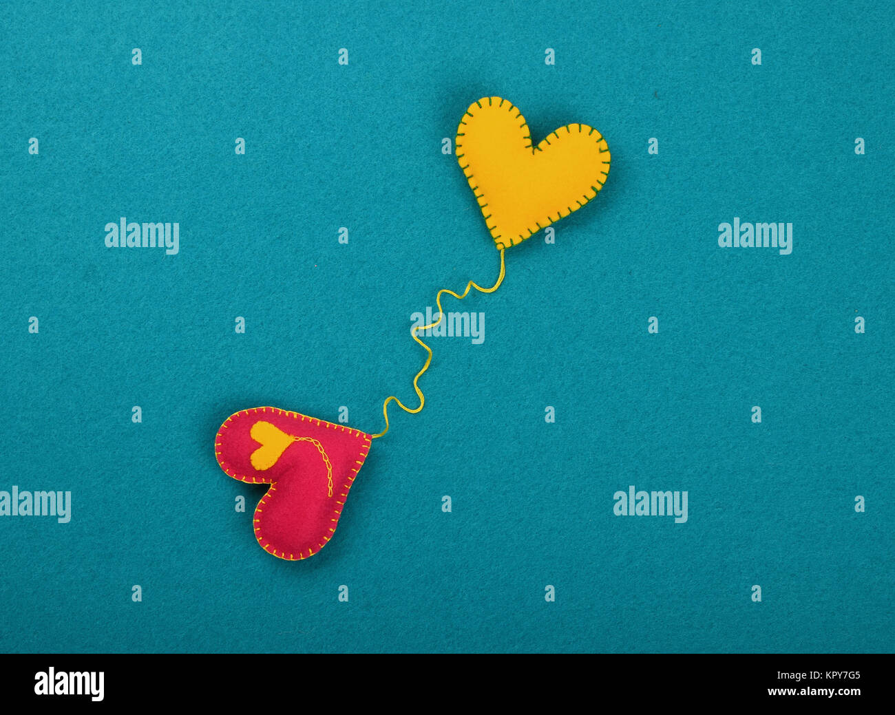 Two felt craft hearts, pink and yellow on blue Stock Photo - Alamy