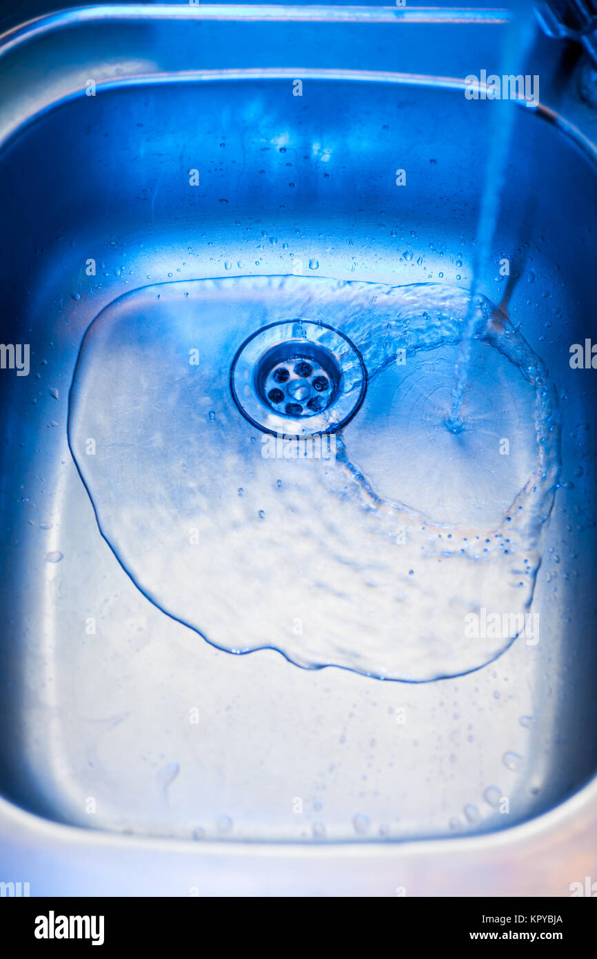 A stream of clean, transparent fresh water flows from the steel shiny ...