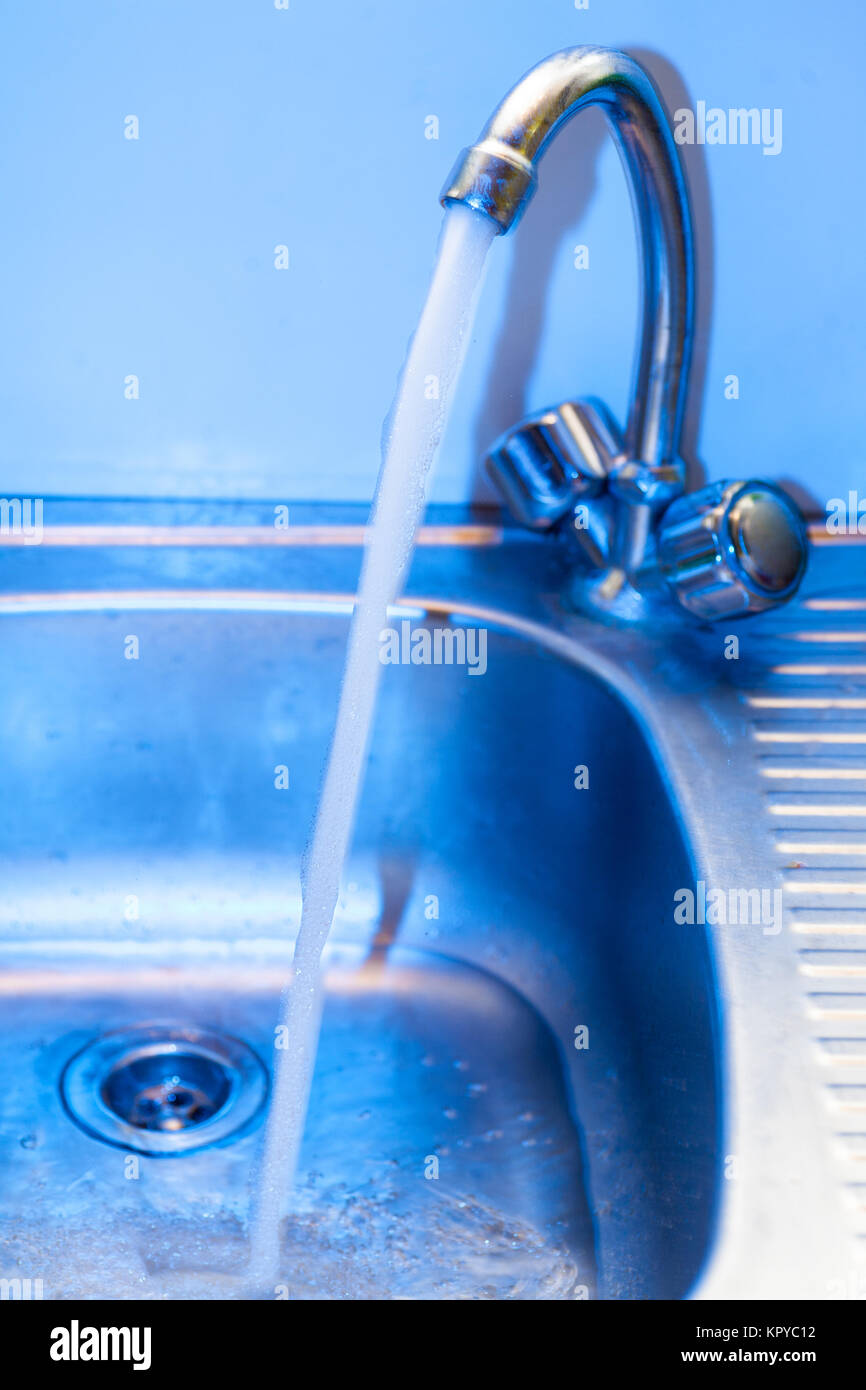 A stream of clean, transparent fresh water flows from the steel shiny ...