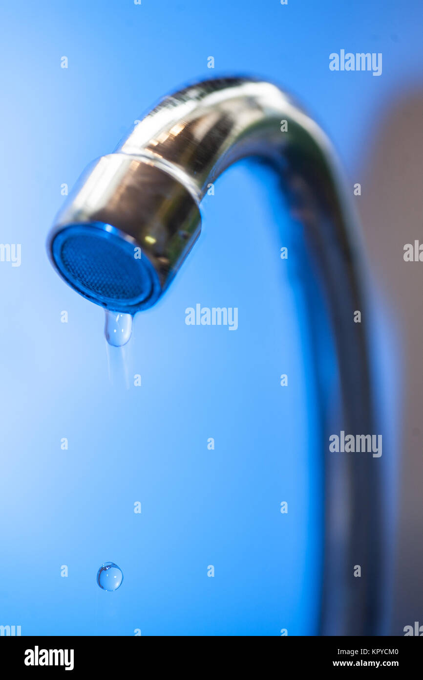 Water drips from the tap into a steel metal shell in blue tones close ...
