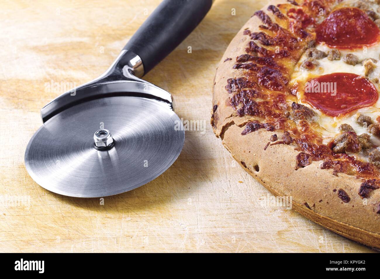 pizza slicer and pepperoni pizza Stock Photo - Alamy