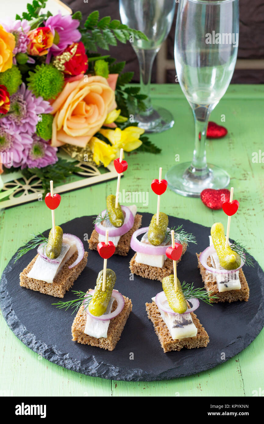Canapes with rye bread, herring and pickles on a festive table ...
