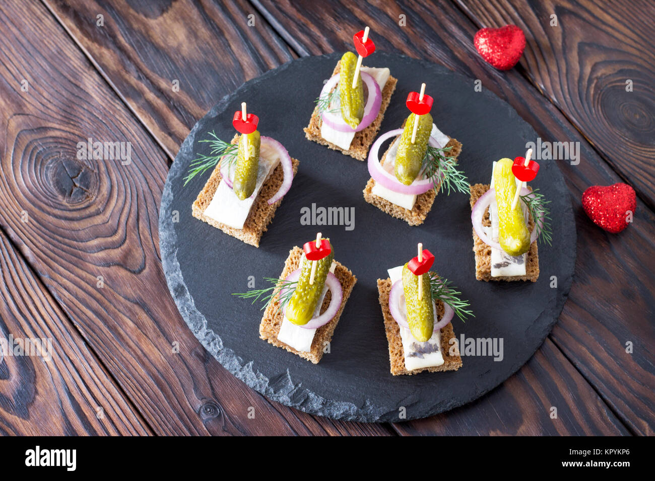 Canapes with rye bread, herring and pickles on a festive table ...