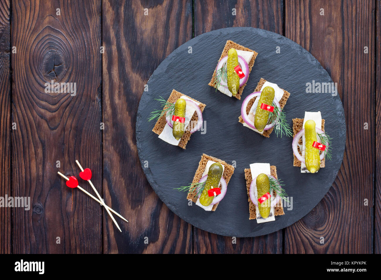 Canapes with rye bread, herring and pickles on a festive table ...
