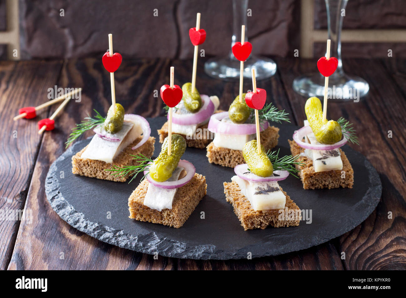 Canapes with rye bread, herring and pickles on a festive table ...