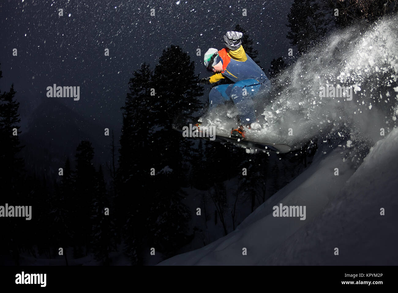 freerider snowboarder jumping at night with a springboard in the forest ...