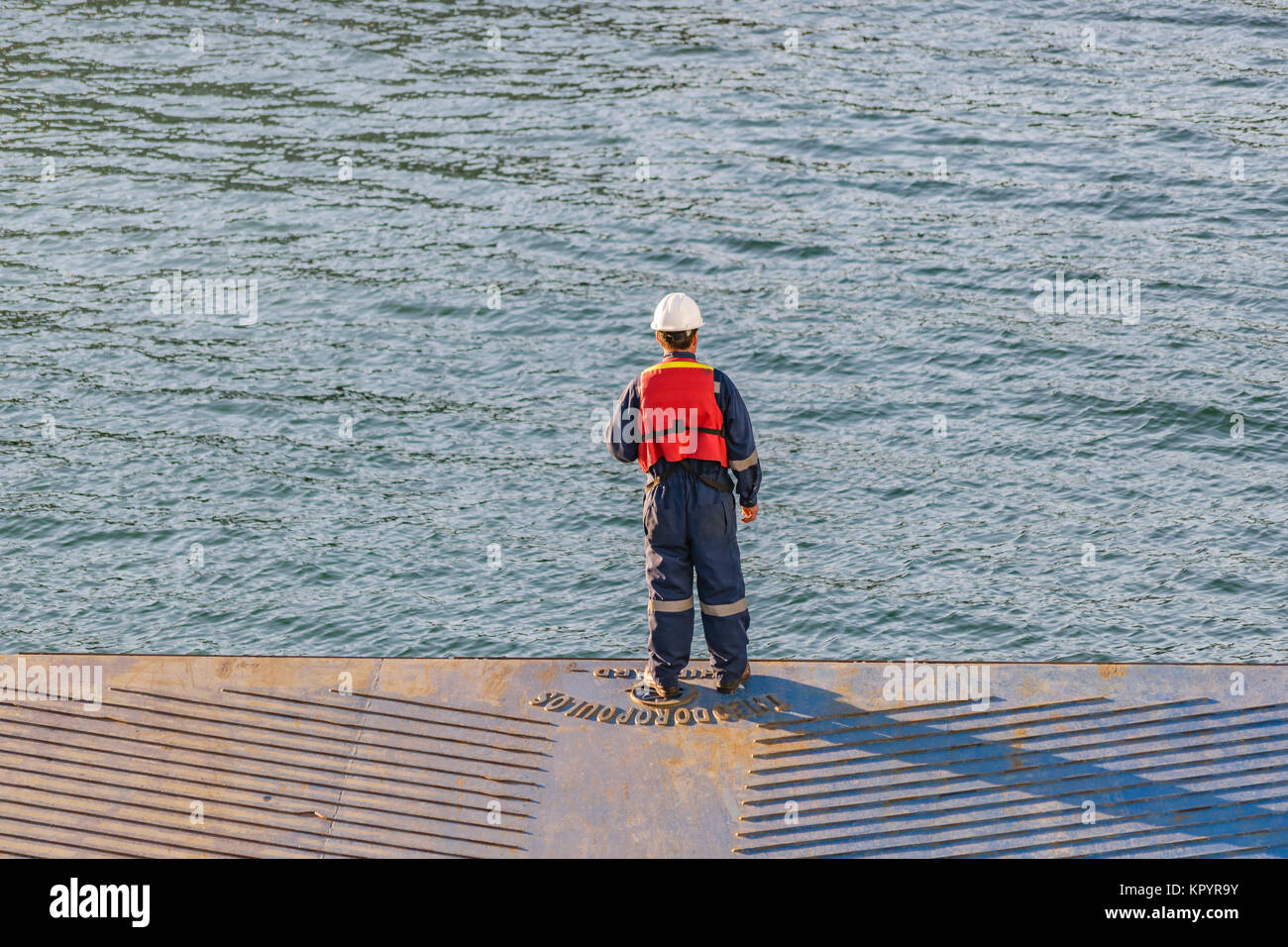 Back view of worker waiting the arrival of ferry Stock Photo - Alamy