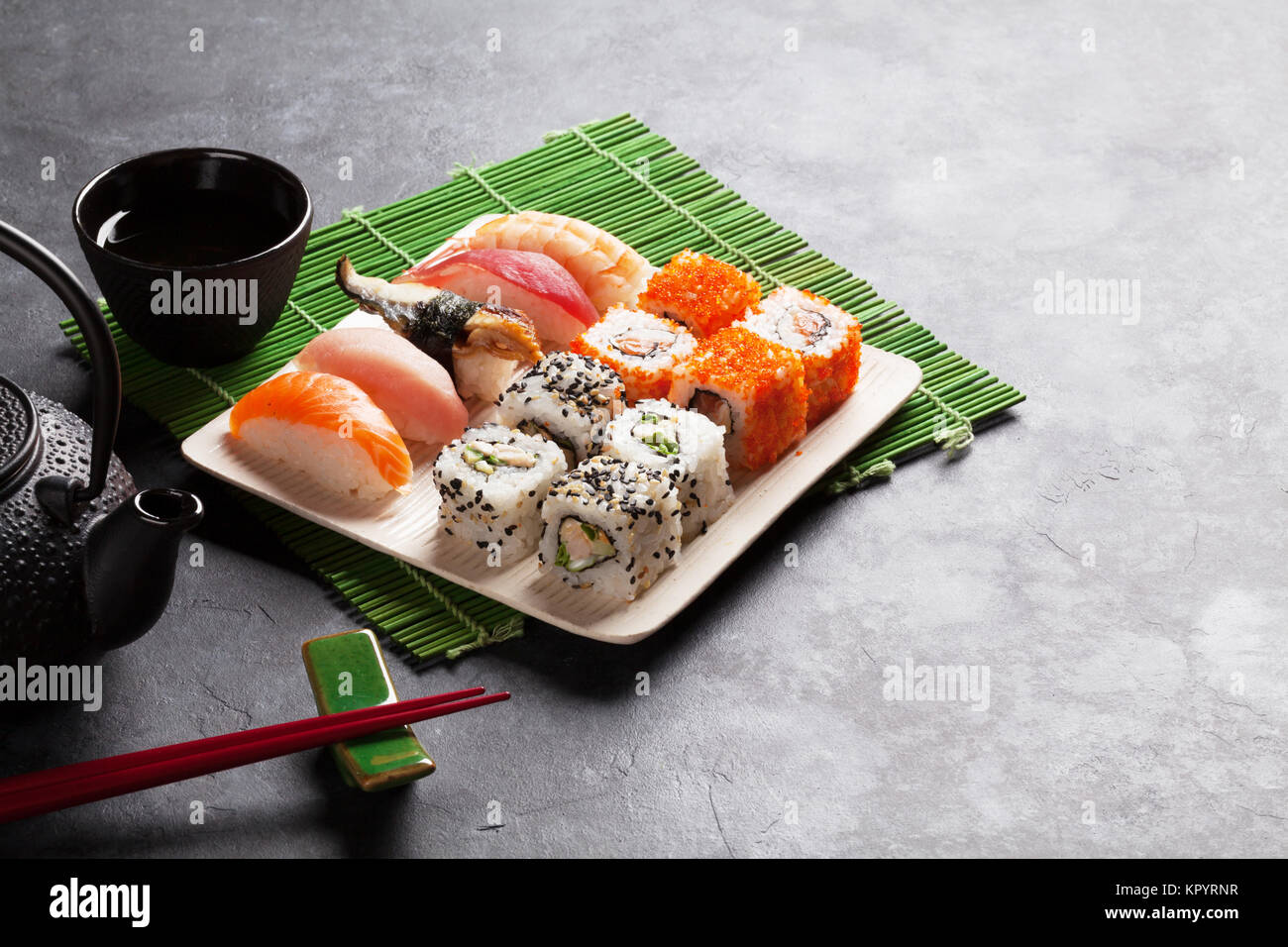 Set of sushi, maki and green tea on stone table. View with copy space ...