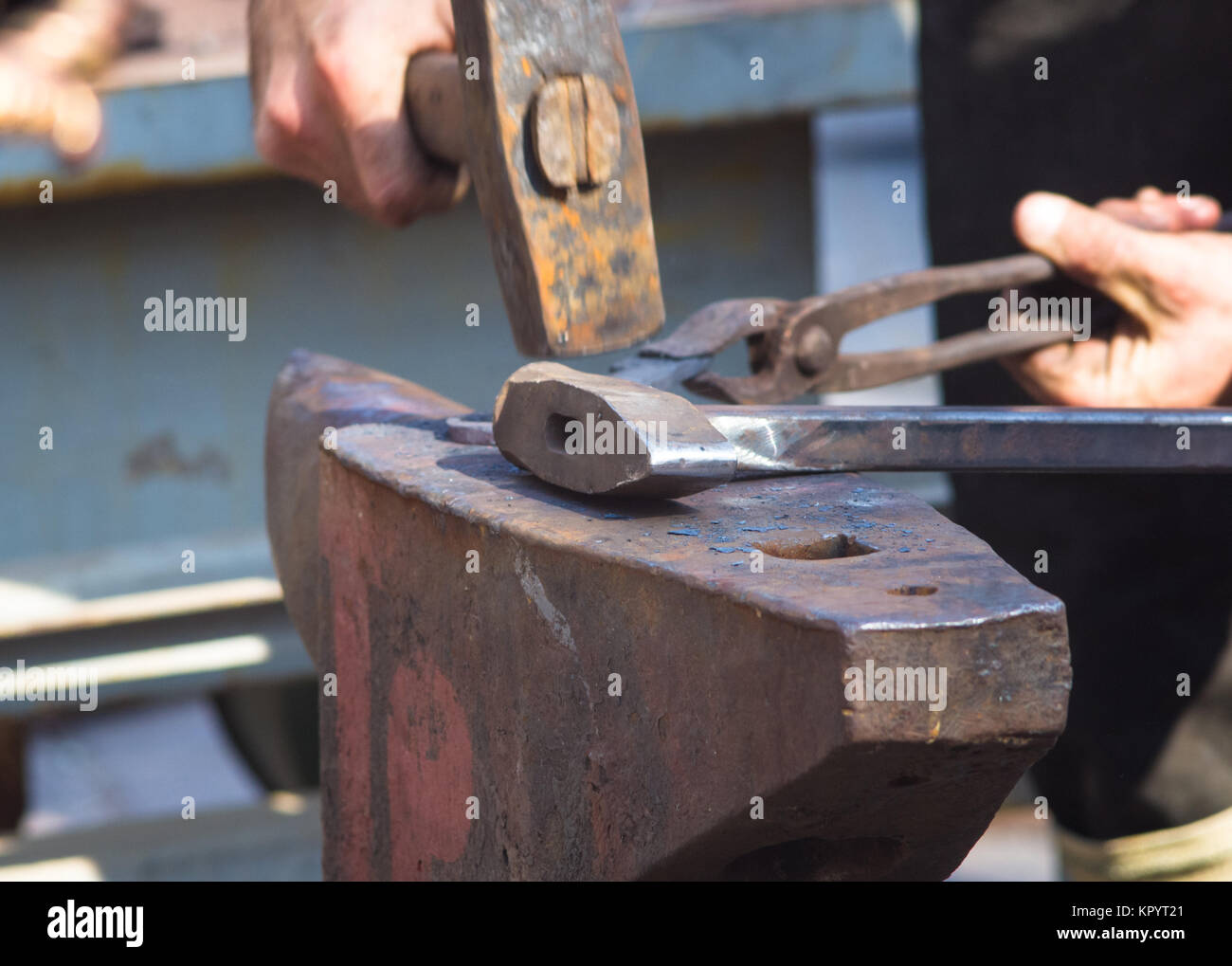 blacksmith performs the forging of hot glowing metal on the anvil ...