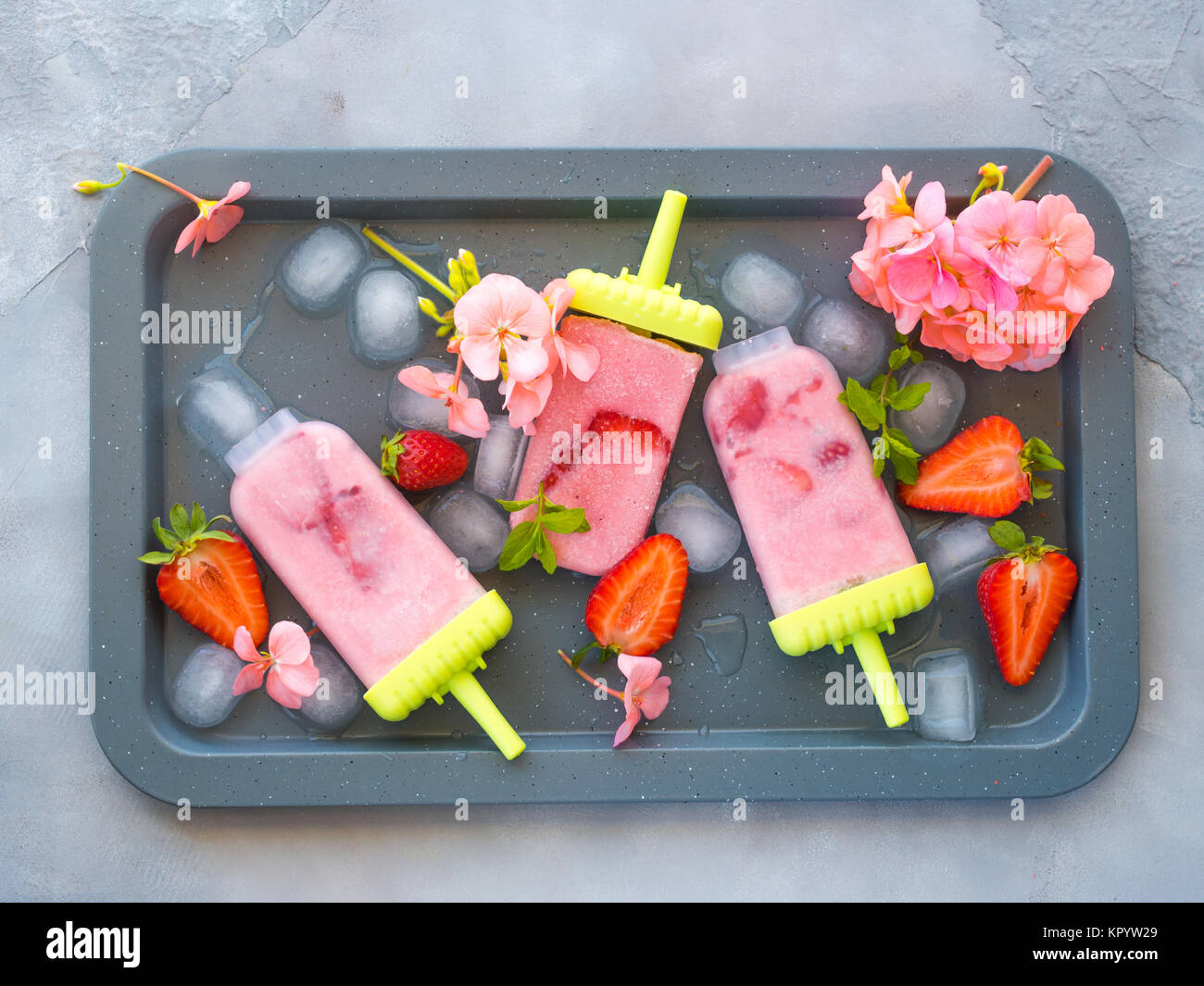 Home made strawberry ice cream popsicles on metall tray with ice cubes ...