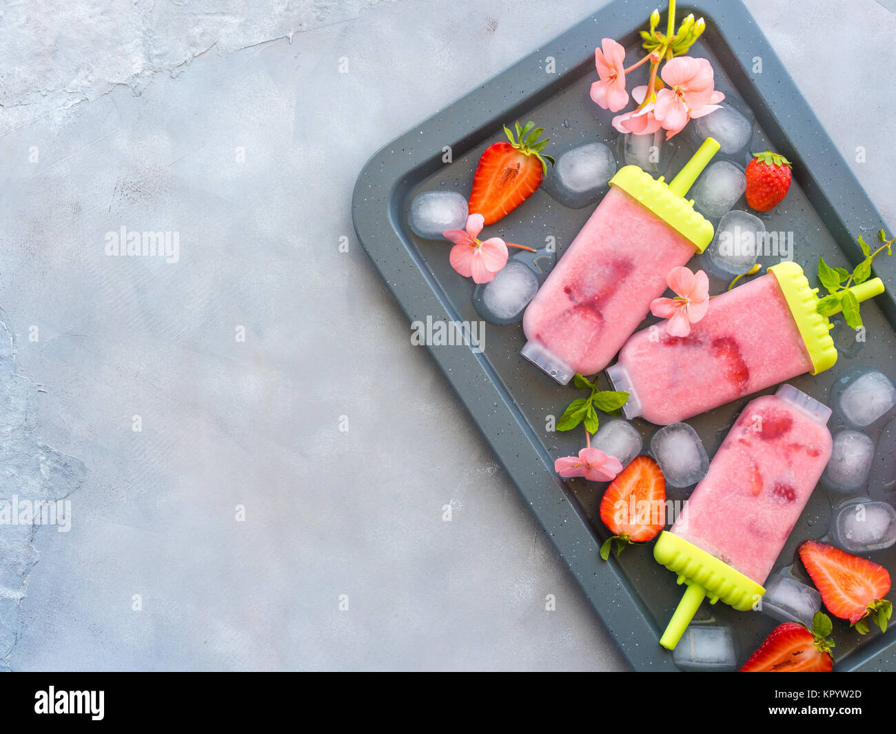 Home made strawberry ice cream popsicles on metall tray with ice cubes ...