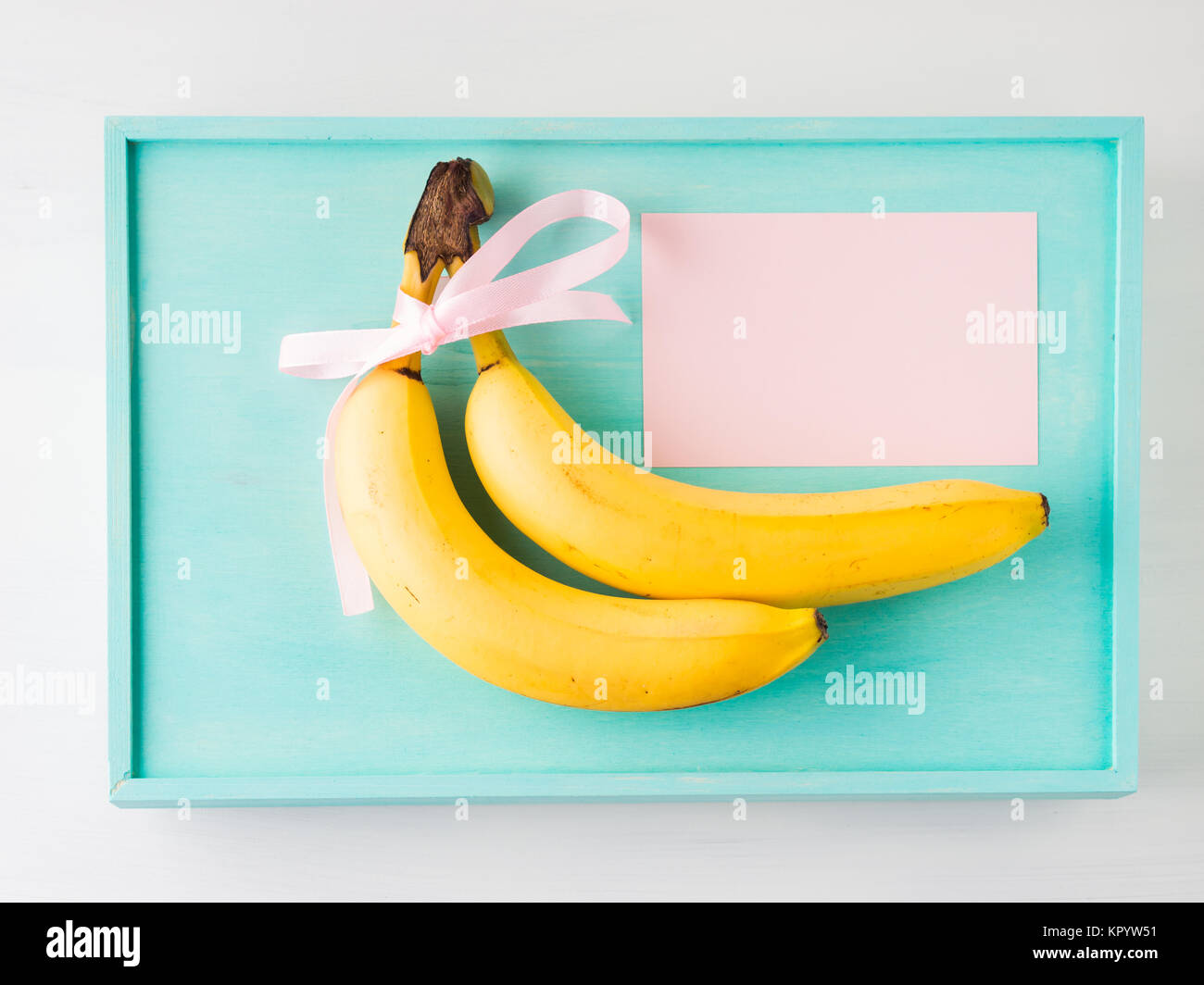 Two bananas with pink ribbon and card on green pastel background Stock ...
