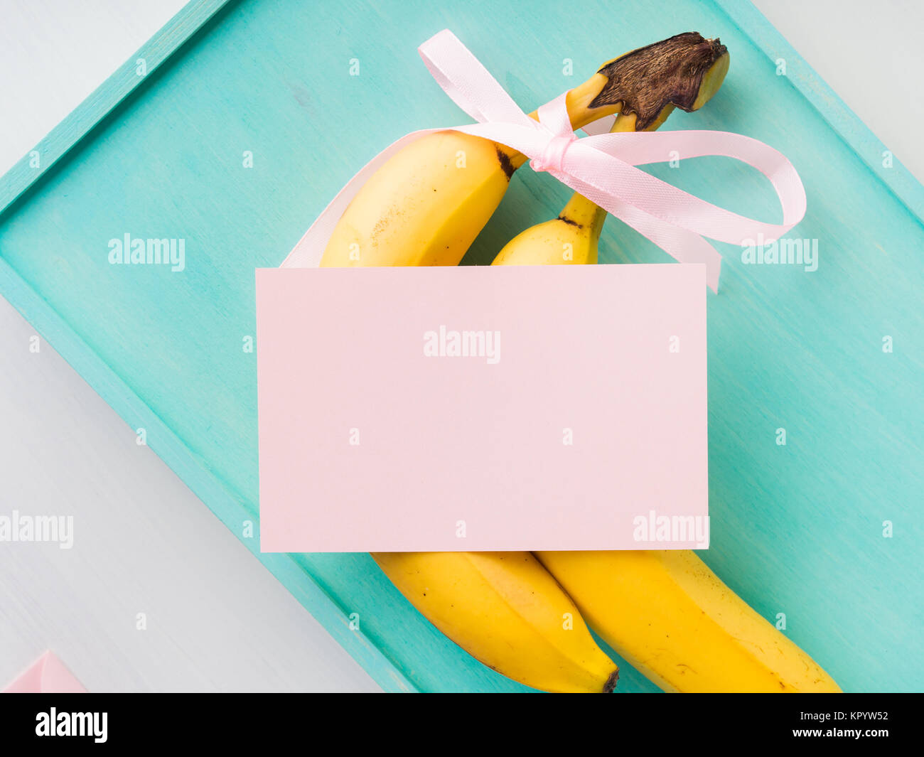Two bananas with pink ribbon and card on green pastel background Stock ...