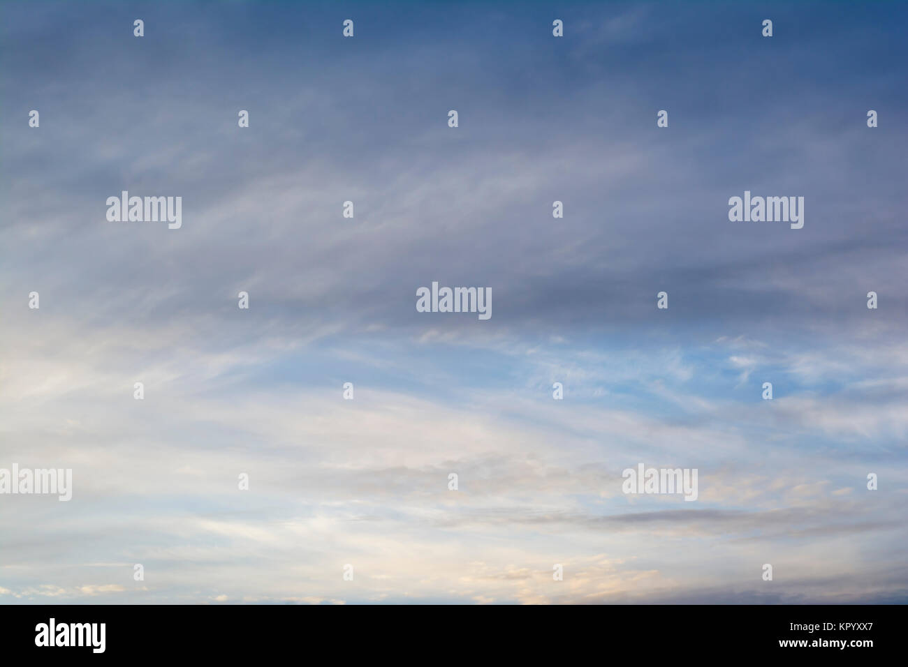 Wispy, translucent clouds against a darkening blue sky just before ...