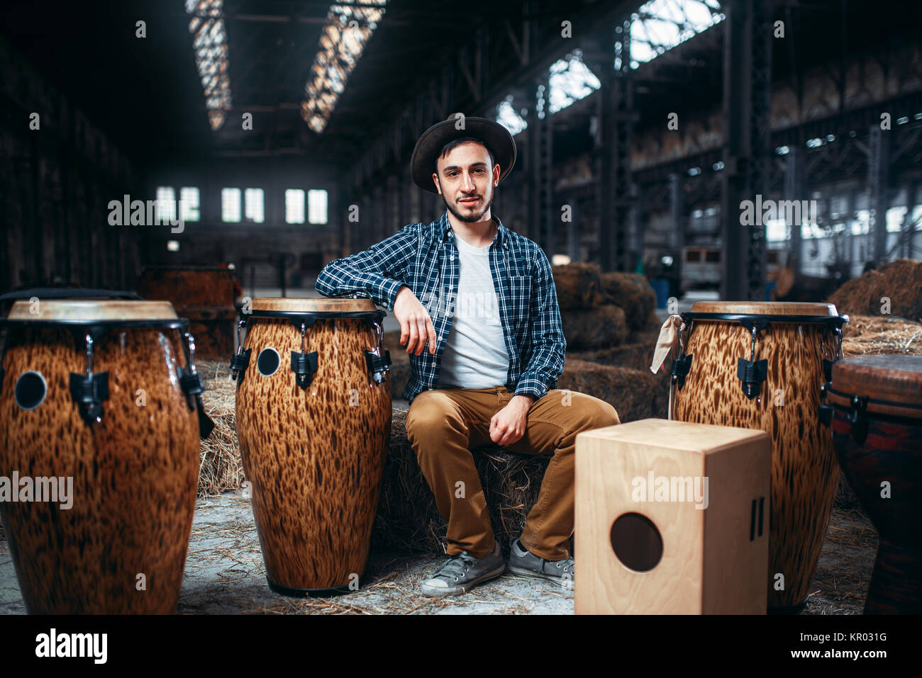 Young male drummer pose against african wooden drum, factory shop on ...