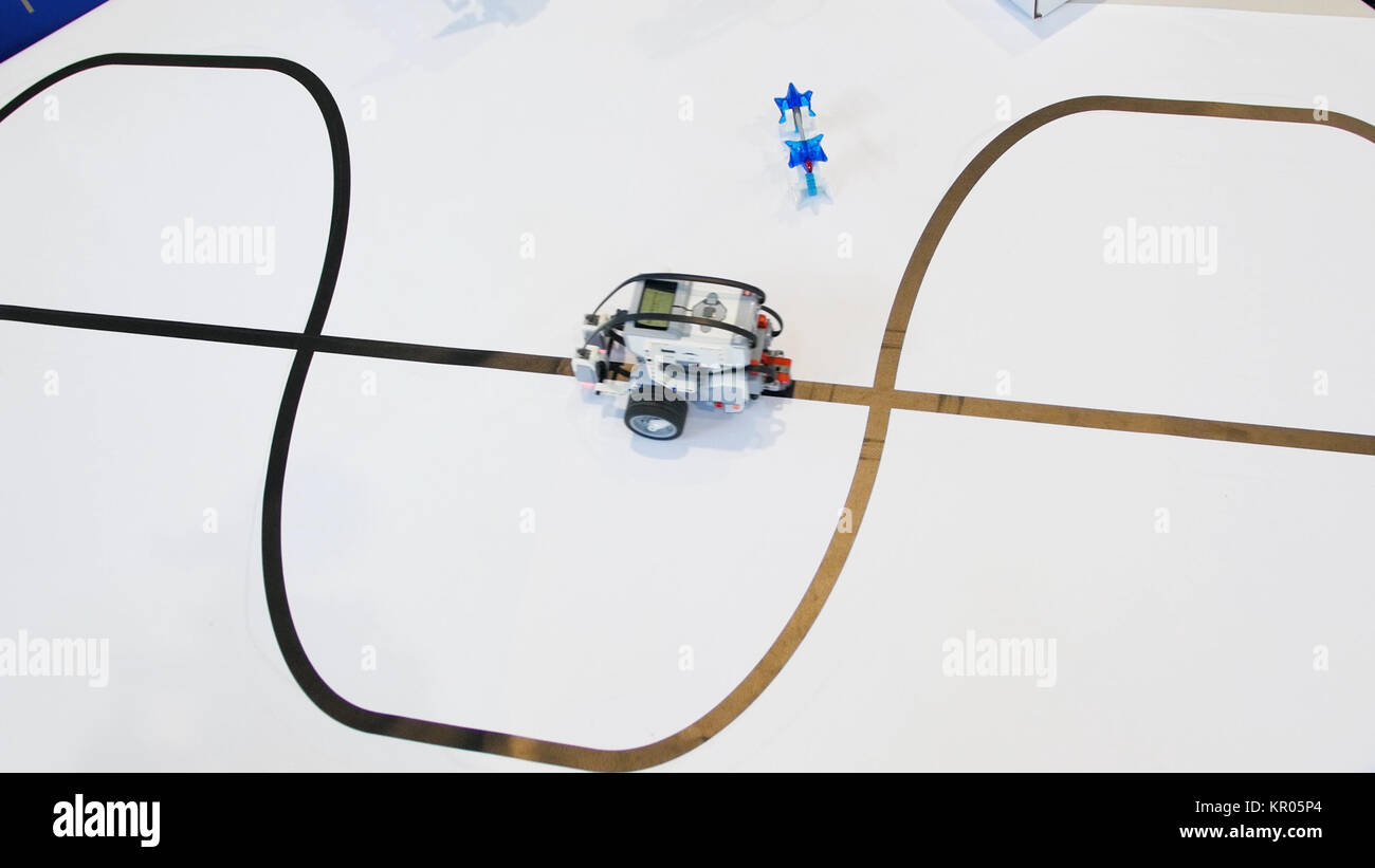 Robot with four wheels rides on a white table. Electric vehicle robot ...