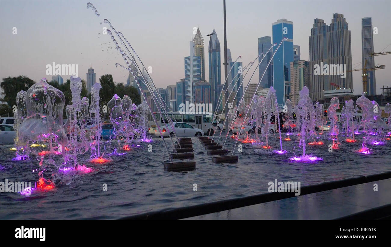 Many small splashing dancing fountains in summer Dubai park. Outdoor ...