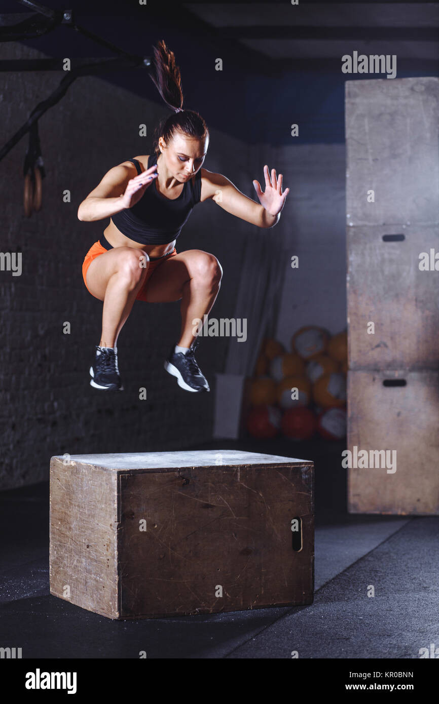 woman box jumping at cross fit gym. athlete doing box jumps exercise at ...