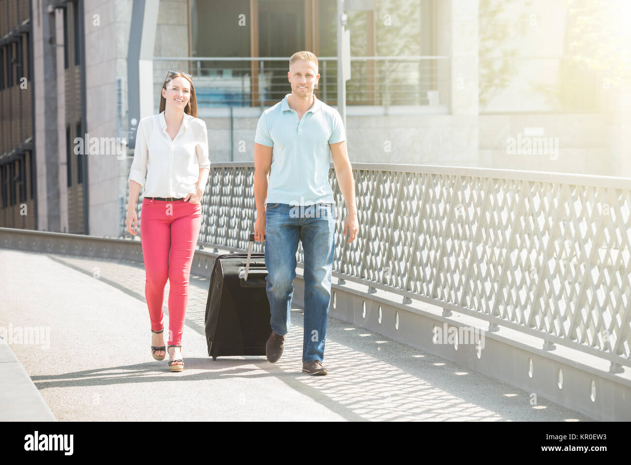 Young Couple Walking On Bridge With Luggage Stock Photo - Alamy