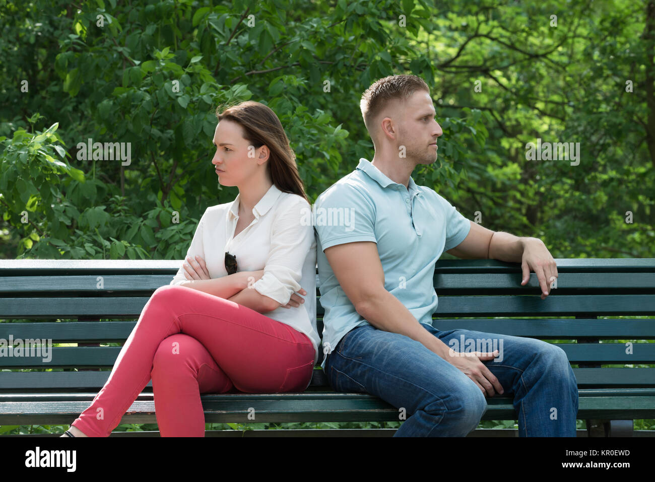 Couple Sitting Back To Back On Bench Stock Photo - Alamy