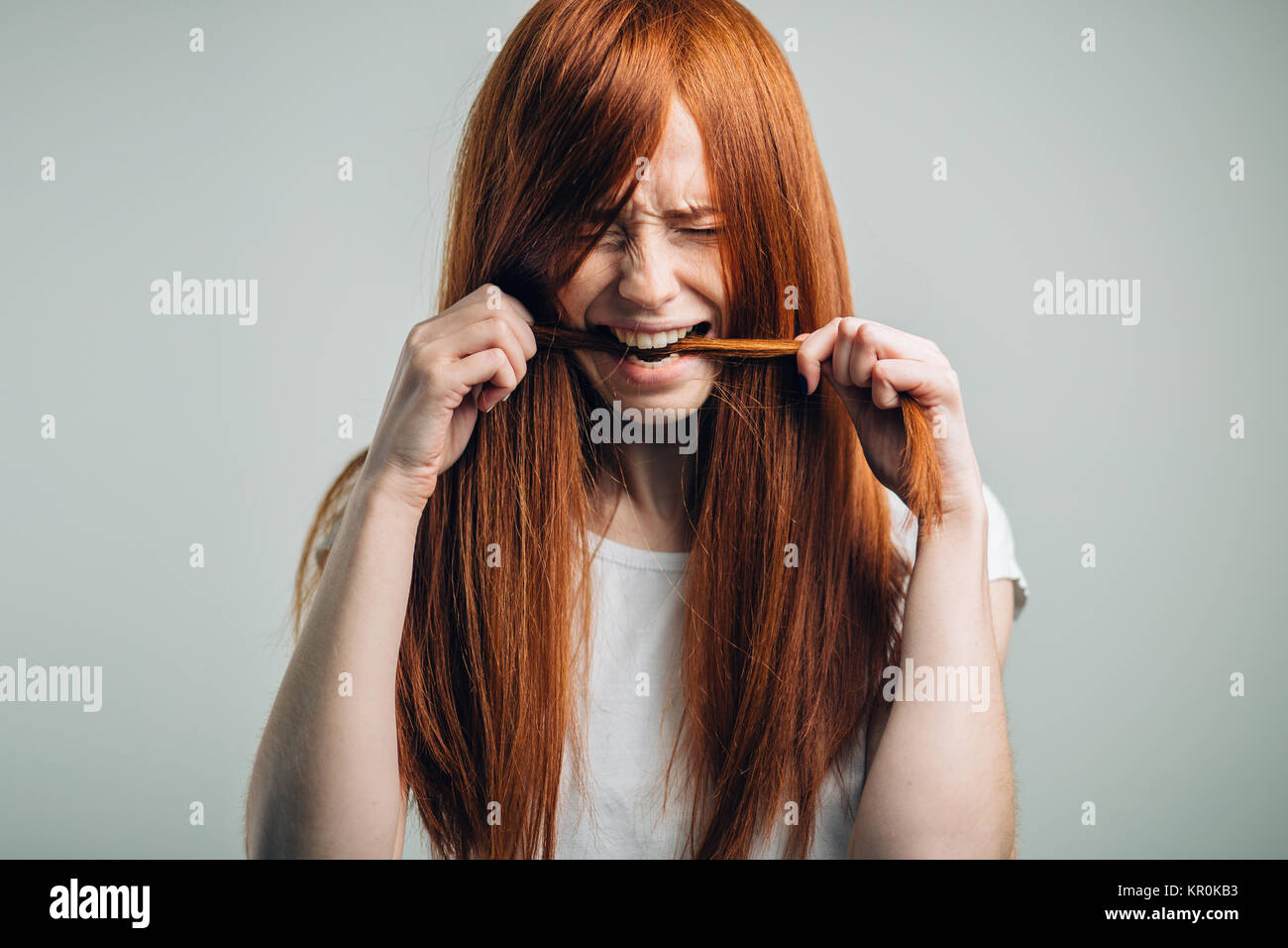 Sad redhead girl bite her damaged hair Stock Photo - Alamy